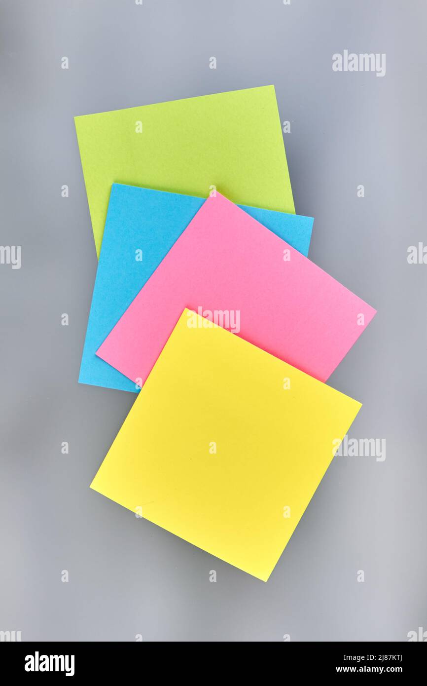 Vertical shot colored sticky paper notes on blurred background. Blank ...