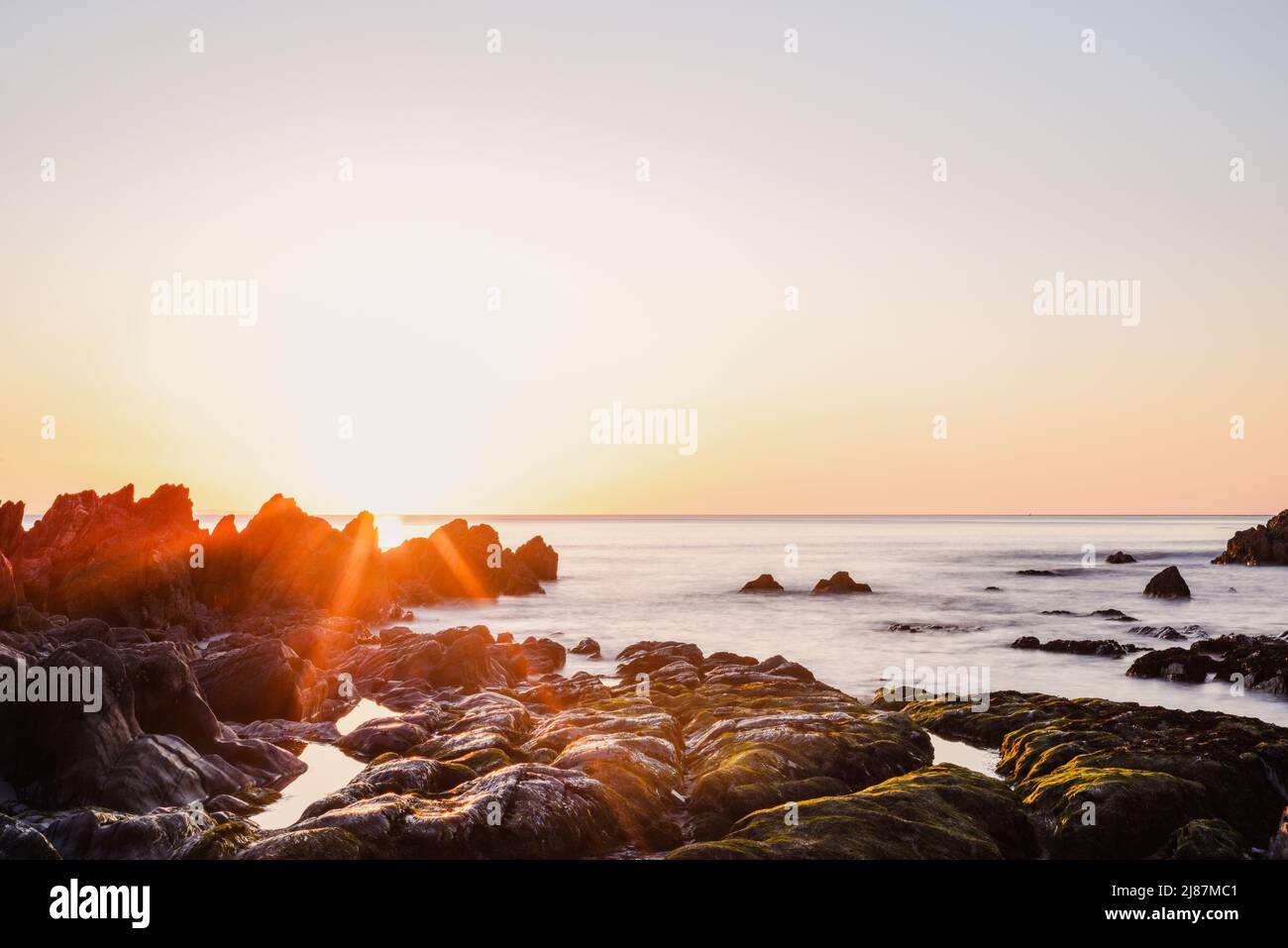 Sunset over the ocean water at low angle beach view Stock Photo - Alamy