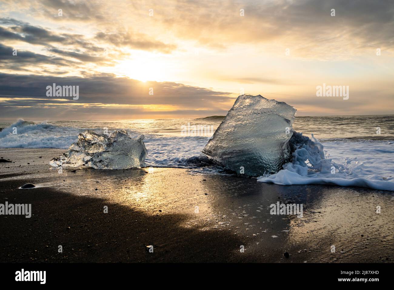 Breathtaking shot of backlit ice chunks washed on the black sand ...