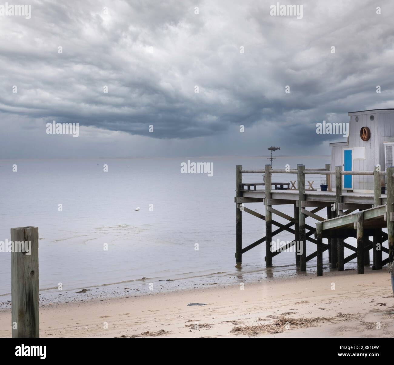 View of Cape Cod harbor house with blue door on wooden dock over the ...