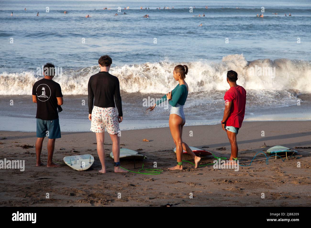 A young couple with their surf instructors surfboards standing at the ...