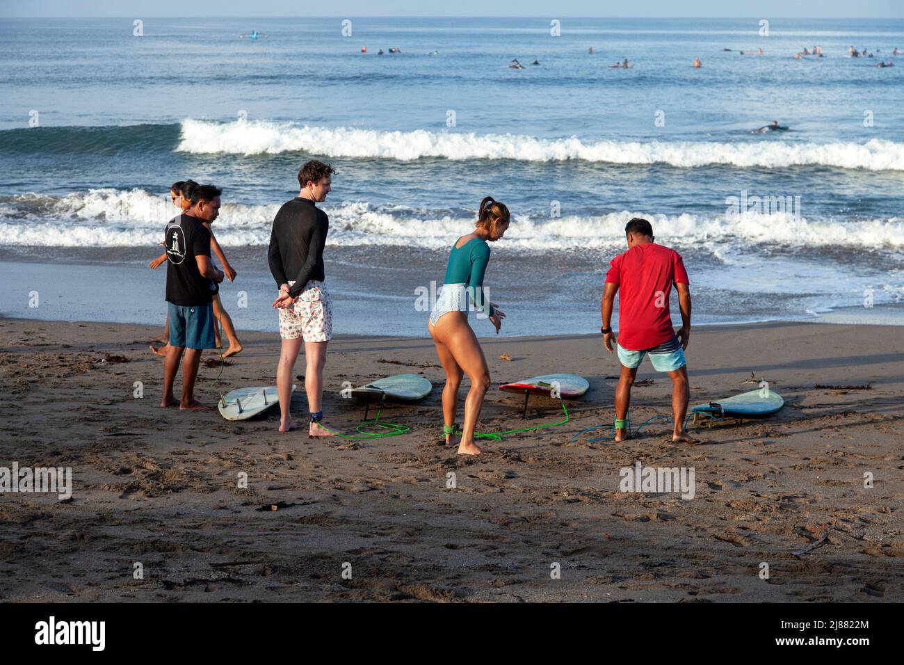 Surf instructors with their students teaching surf moves before going ...