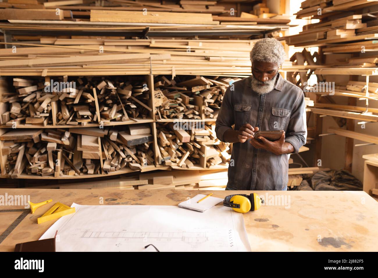 African american mature carpenter working on tablet pc in workshop ...