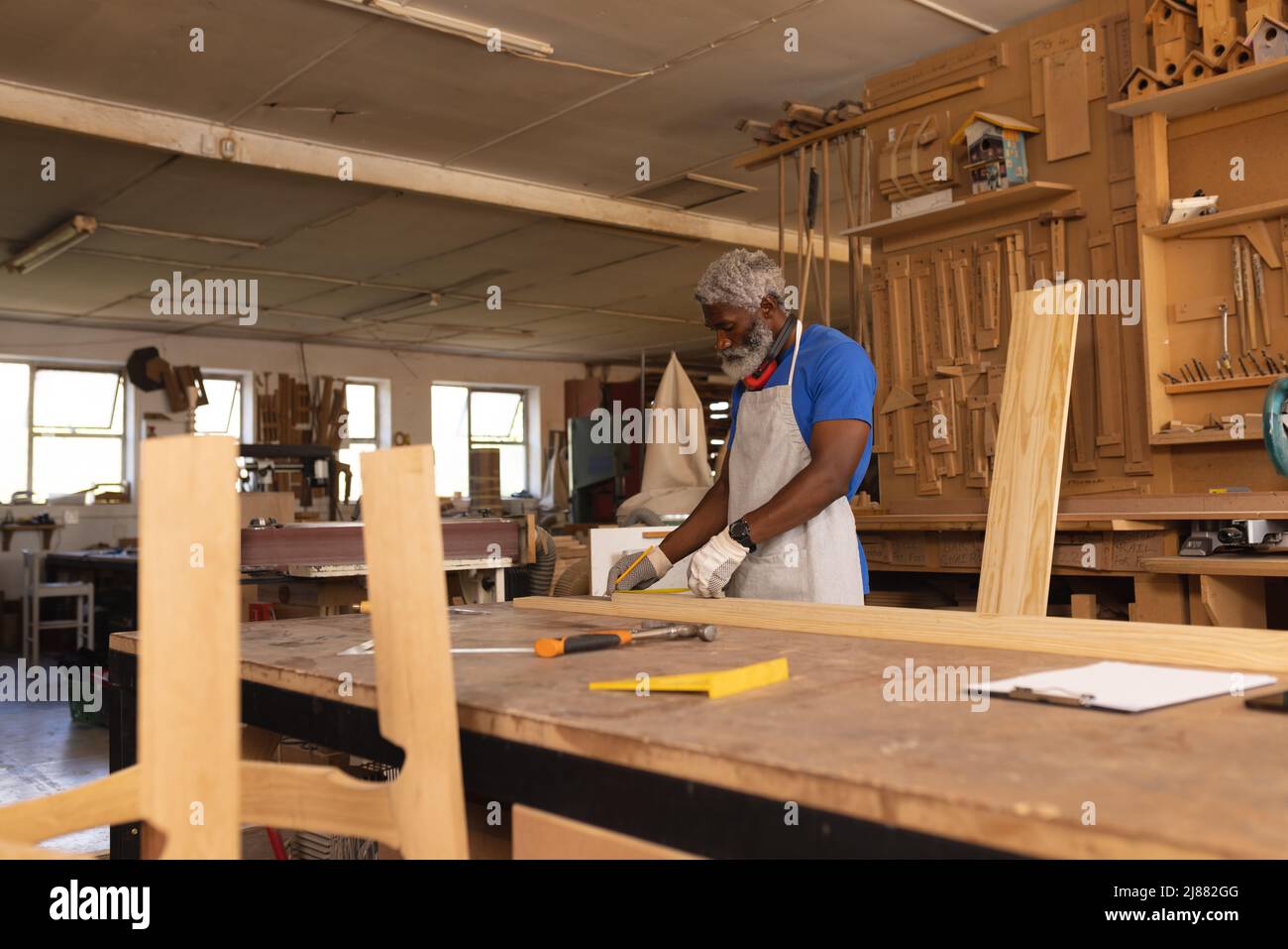African american mature carpenter marking on plank at workbench in ...
