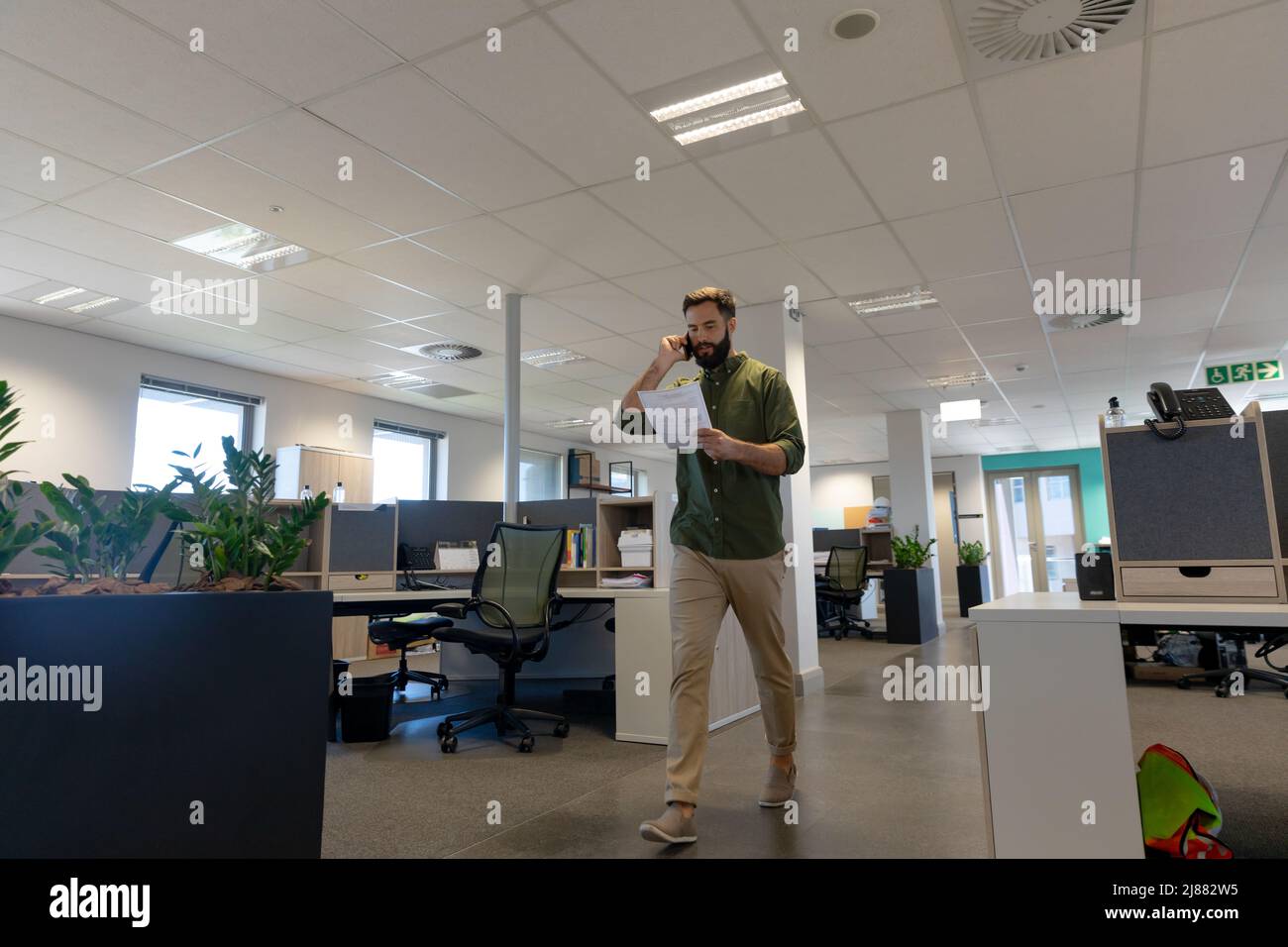 Full length of businessman walking with document while talking on ...