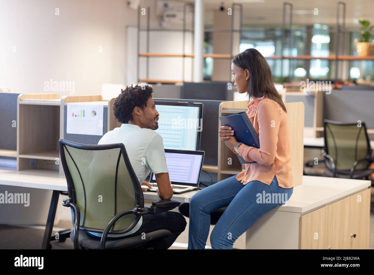 Biracial business colleagues discussing together while sitting at ...