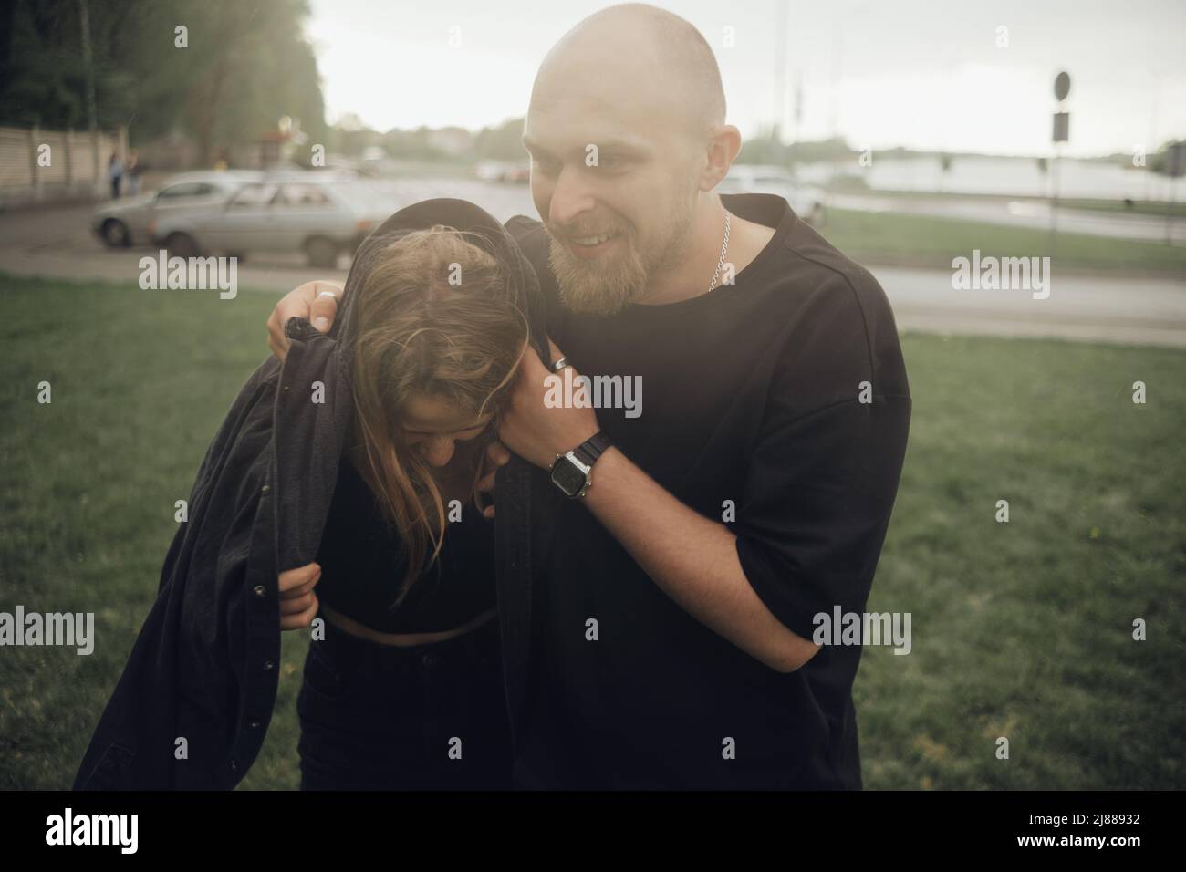 a couple in love is fleeing the rain. the guy covers the girl with his ...