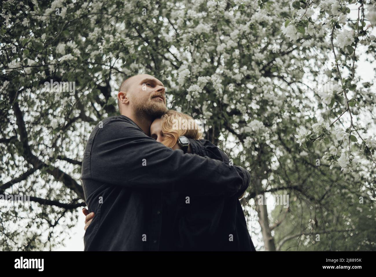 lovers embrace under a flowering tree hiding from the rain Stock Photo ...