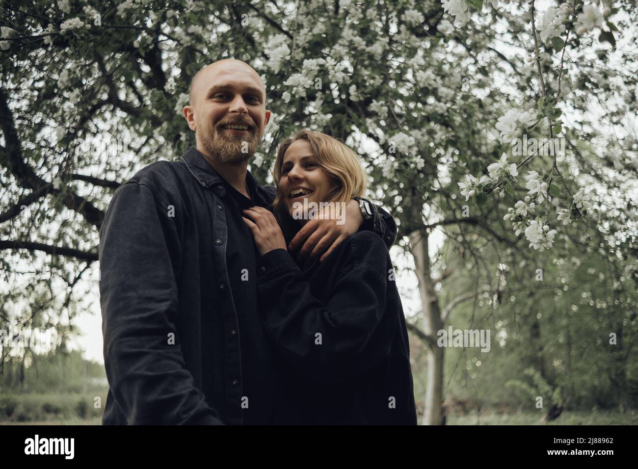 lovers embrace under a flowering tree hiding from the rain Stock Photo ...