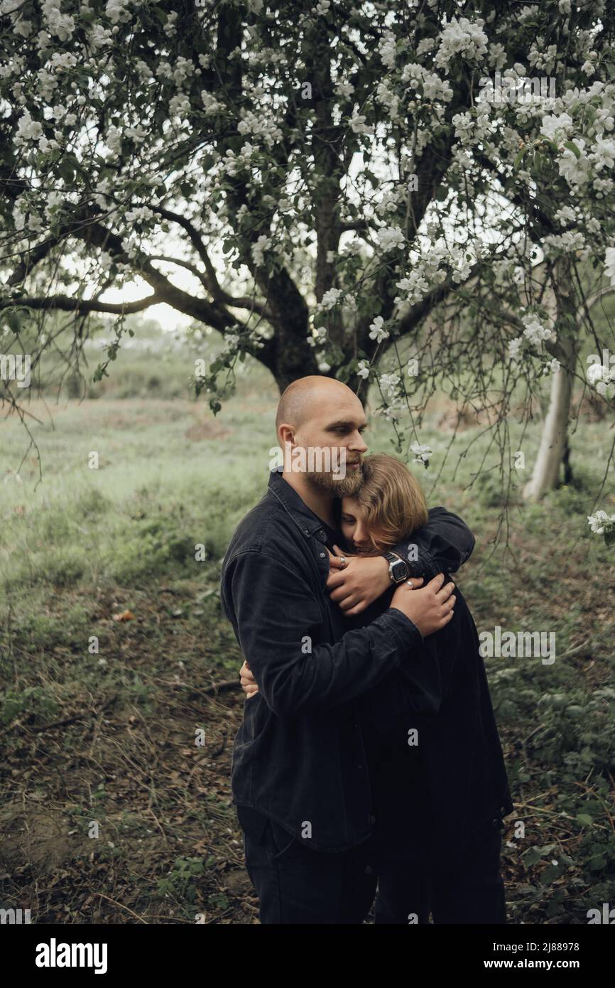 lovers embrace under a flowering tree hiding from the rain Stock Photo ...