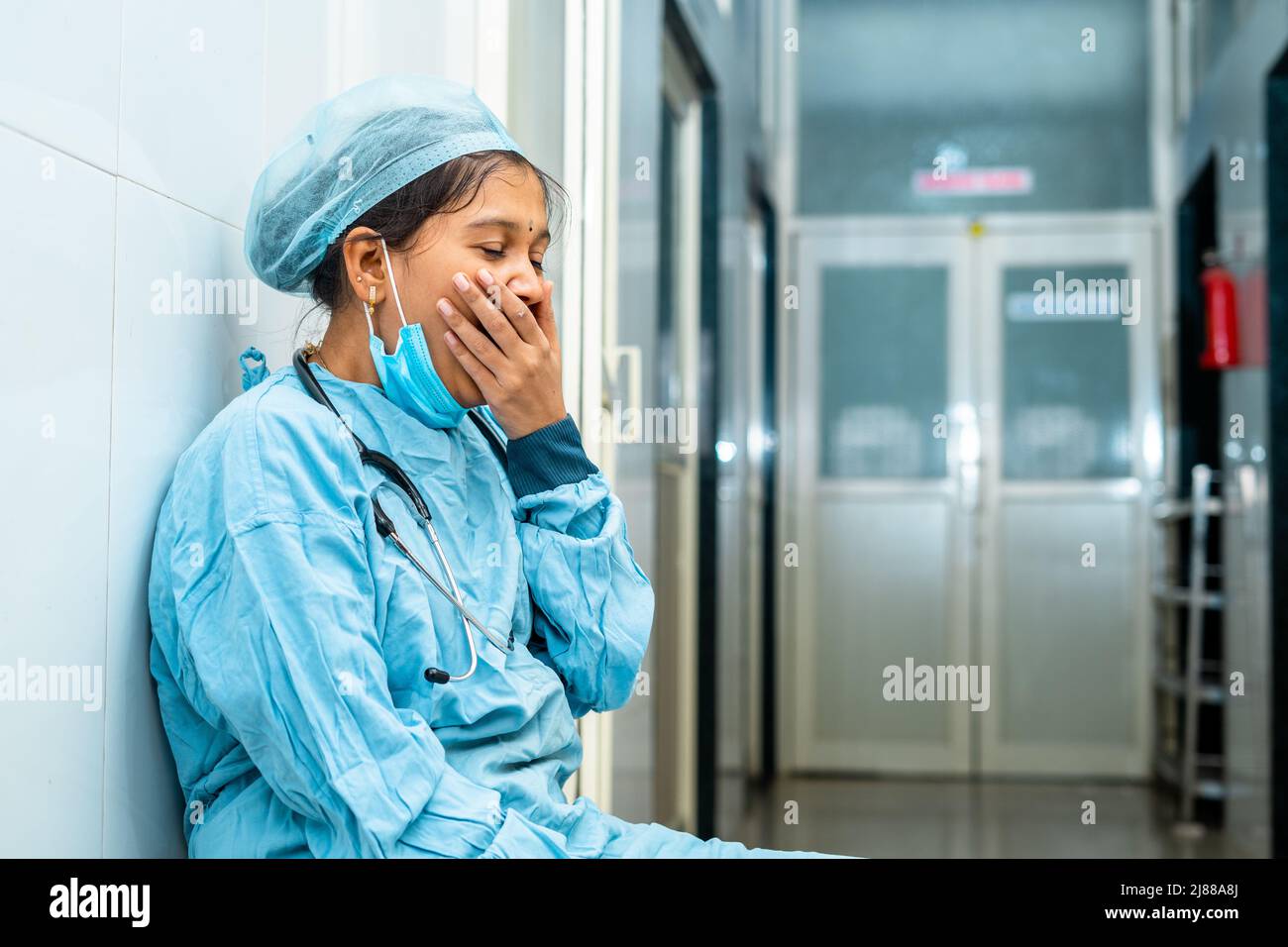 yawning surgeon while sitting at hospital corridor after surgery near ...