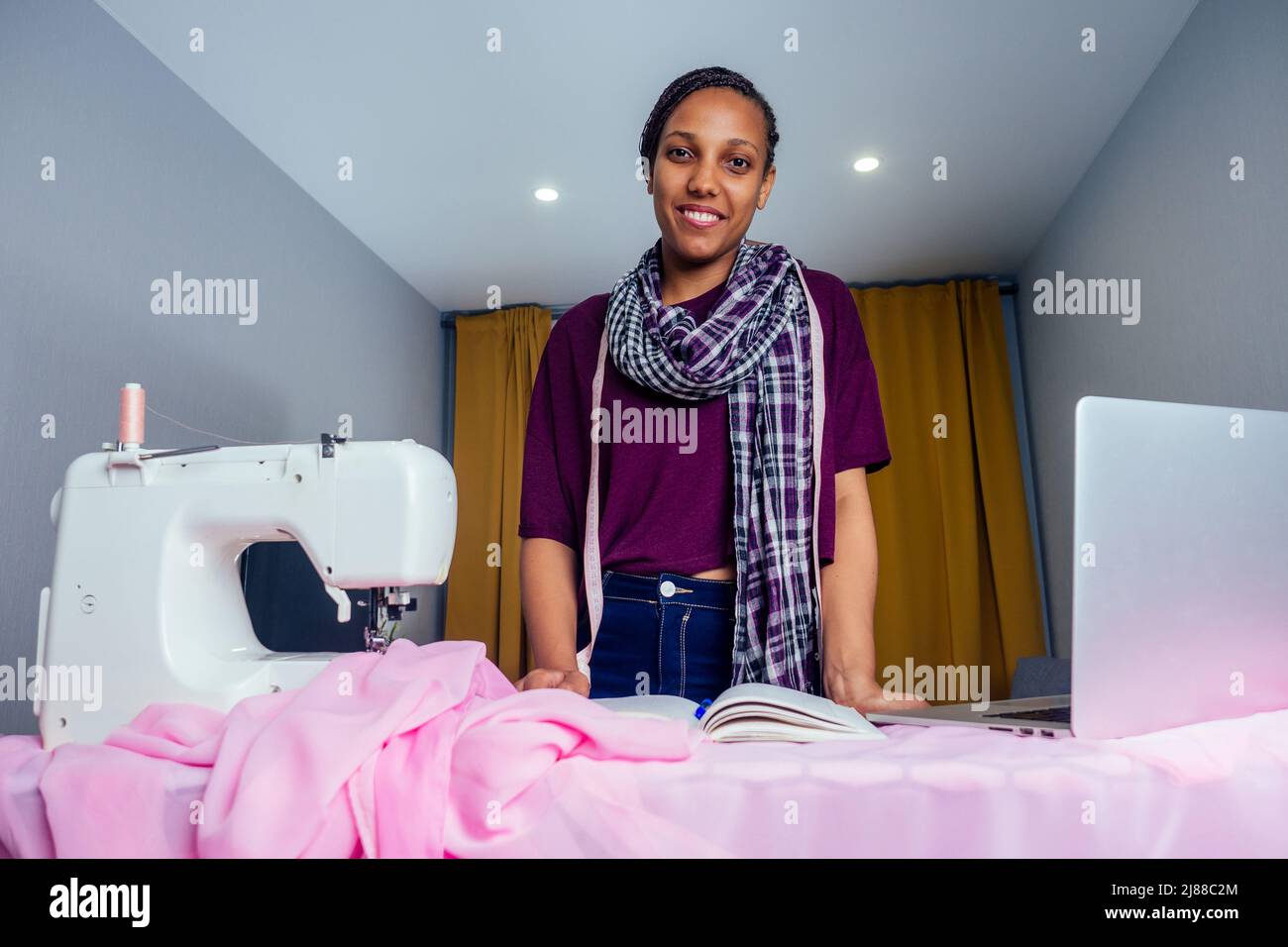 attractive woman seamstress next to the mannequin with sewing machine ...