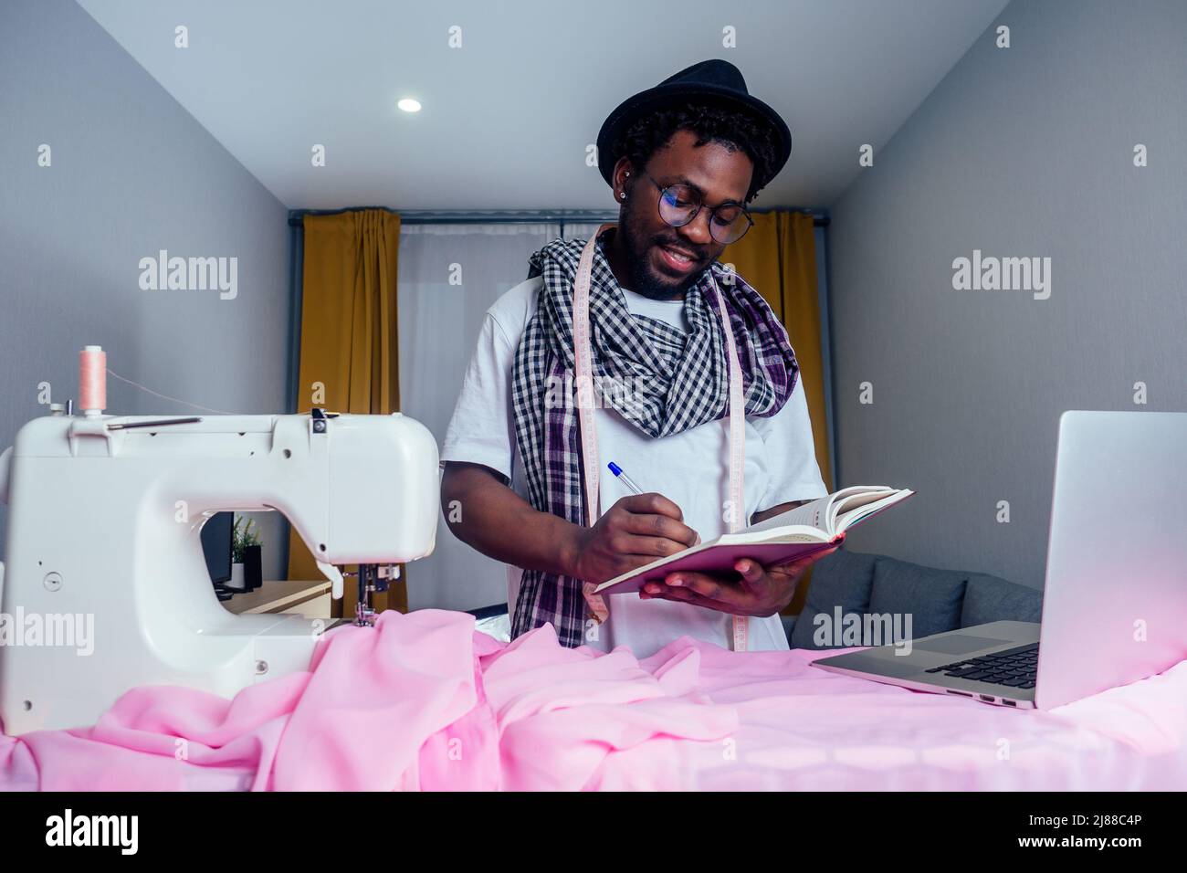 portrait of a handsome african man smiling seamstress with sewing ...