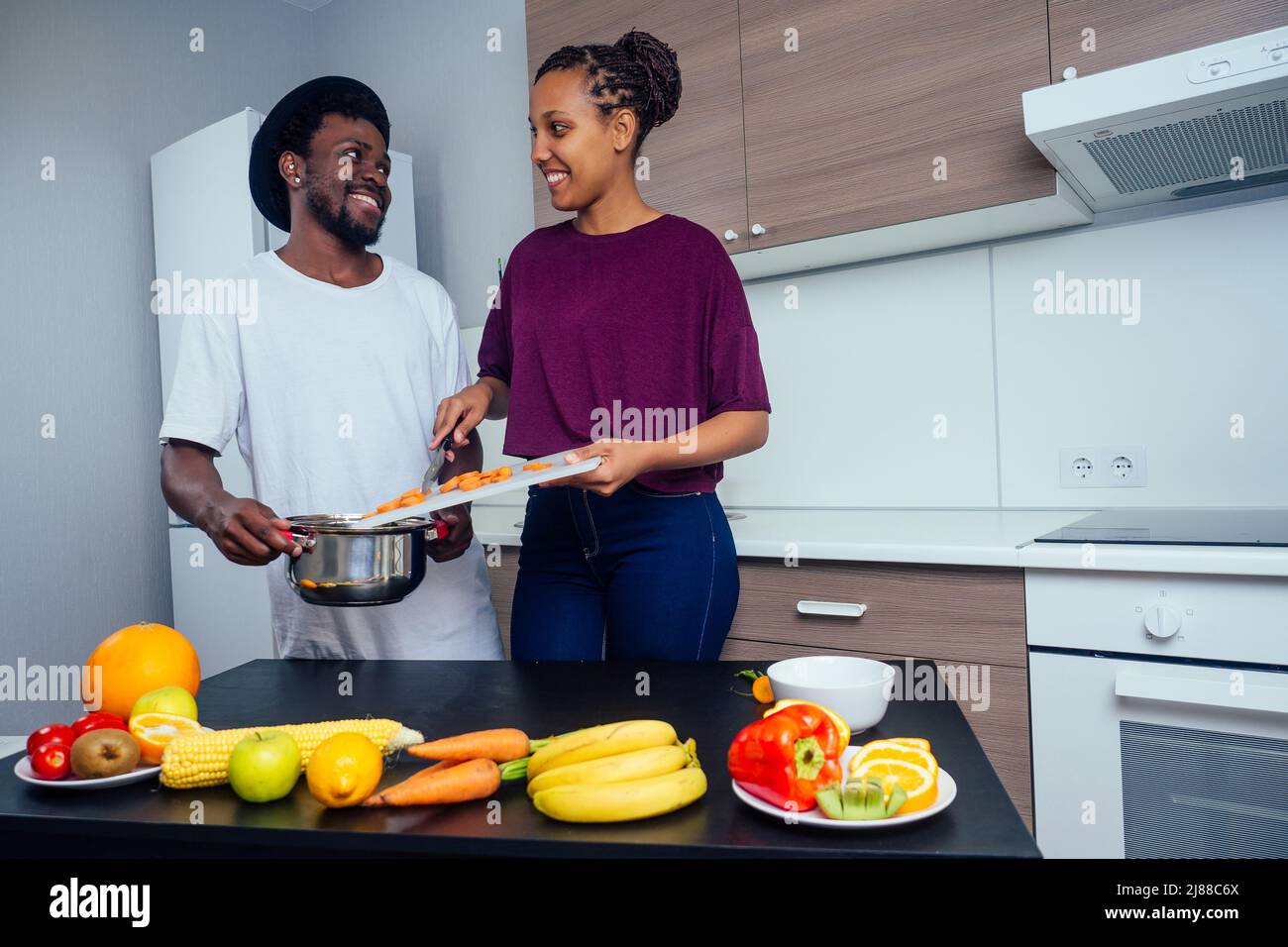 Happy african american love couple cooking fruits salad at kitchen ...
