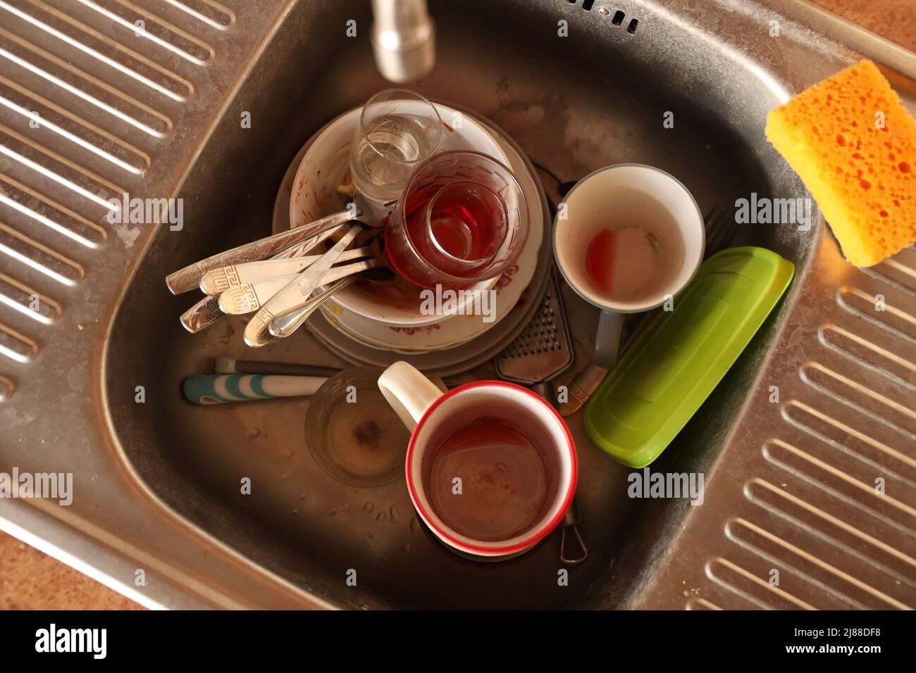 Stack of dirty dishes with food leftovers in the kitchen sink. Unwashed ...
