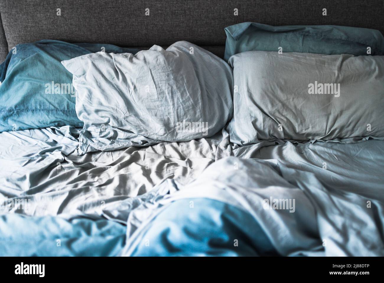 messy queen size bed with light blue quilt cover and sheets looking ...