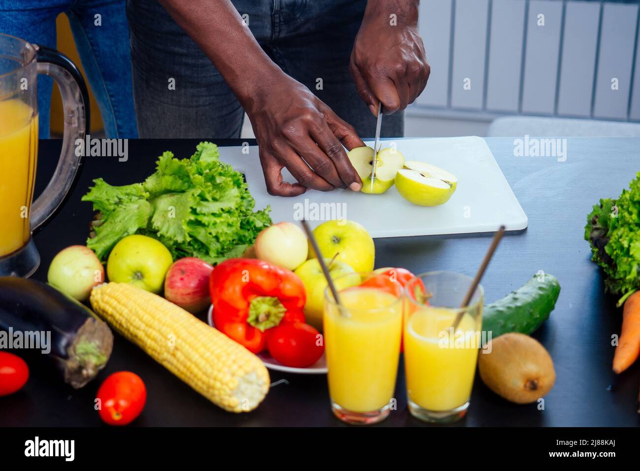 close up photo of afro male hamds cutting apple,eggplant and kivi Stock ...