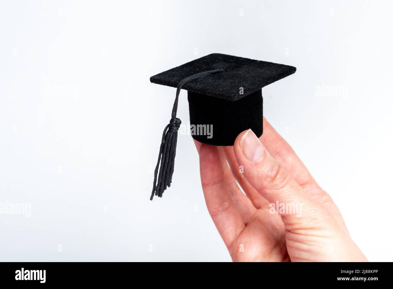 A hand holding a miniature cap of a graduate of a higher school ...
