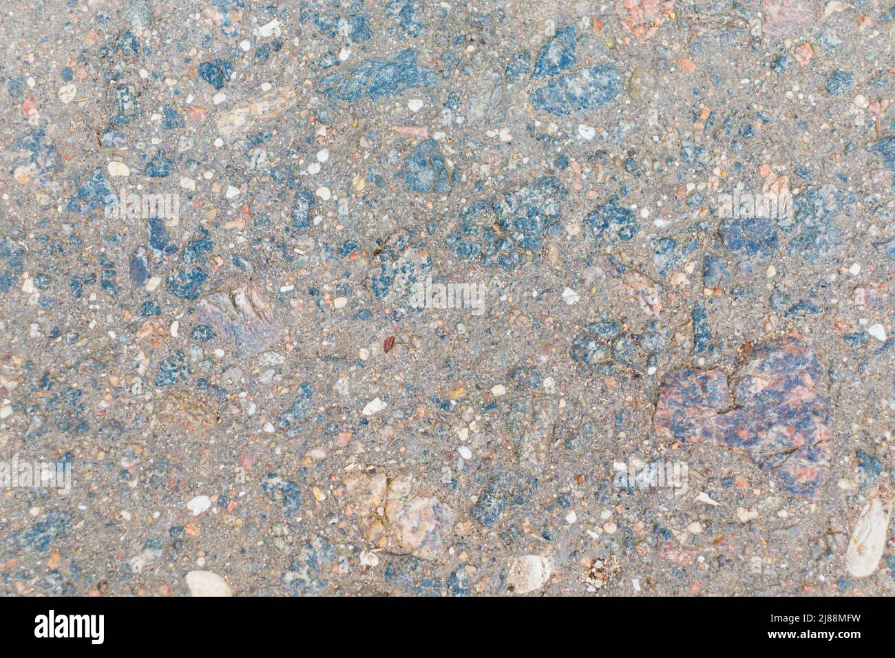 Texture of old hackneyed asphalt. Exposed bluish pebbles peeking out of ...