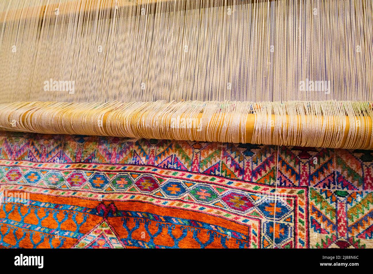 A detail, close up of a loom in the middle of weaving a colorful red ...