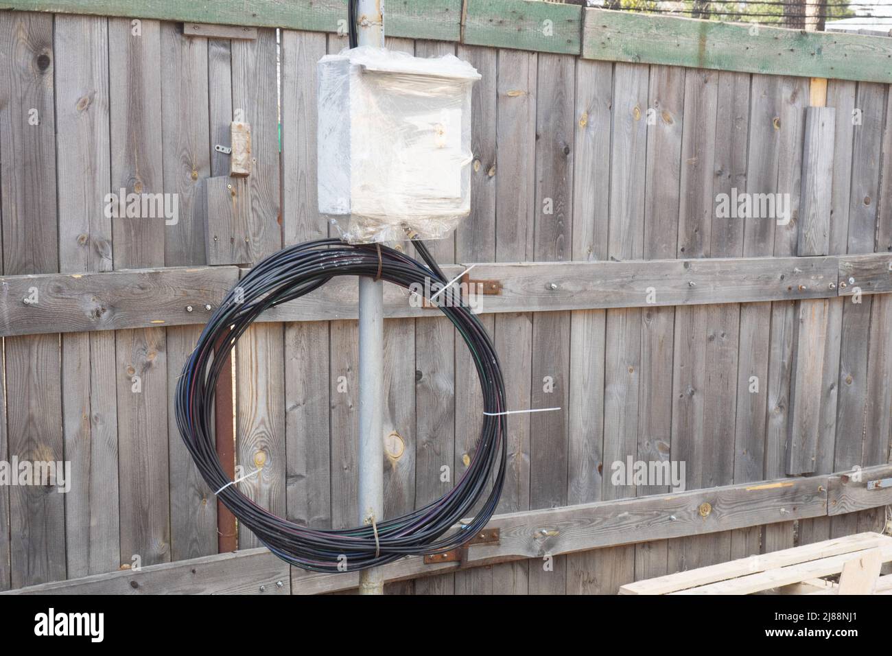 Electrical panel wrapped in cellophane film and a coiled black cable ...