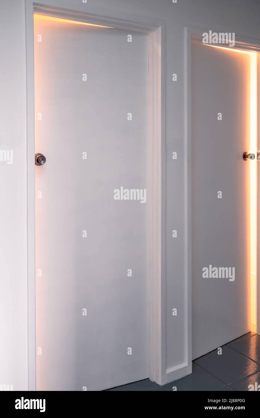 interior corridor with two white doors left ajar and light shining from ...