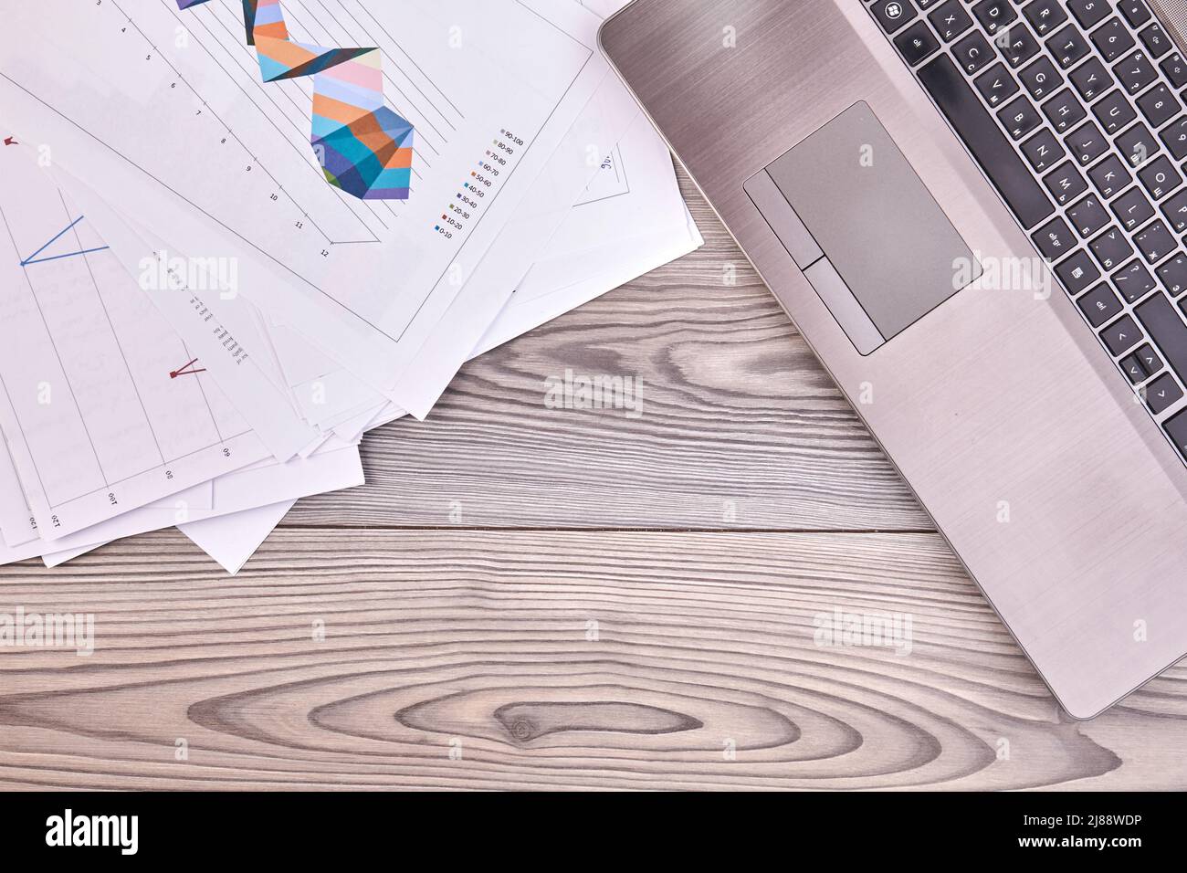 Paperwork with charts with laptop pc on wooden desk. Top view flat lay ...