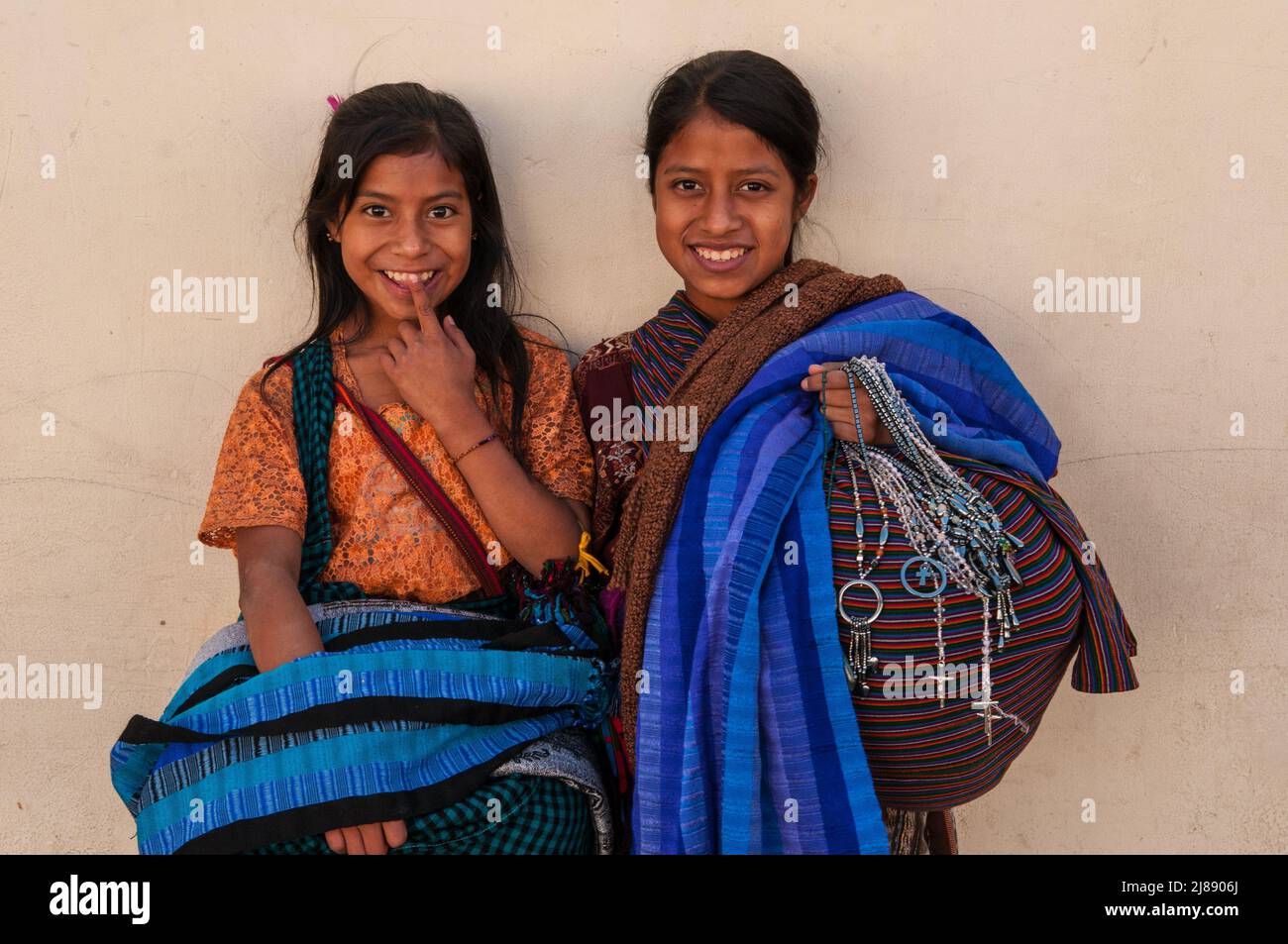 Portrait of 2 Mayan girls w/ colorful textiles, street vendors, smiling ...