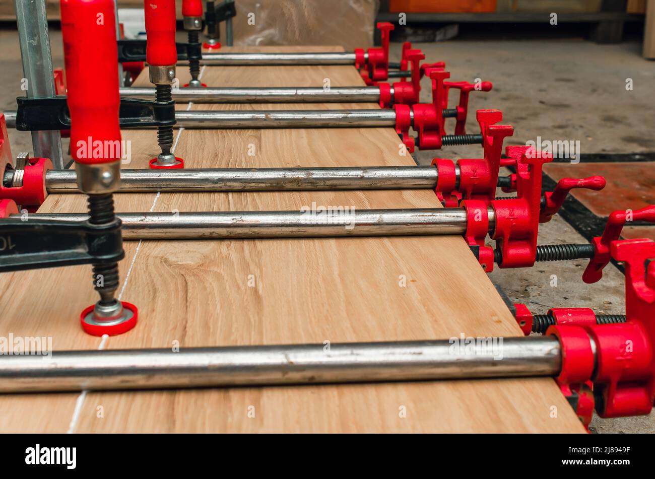 Close up of carpenter fastening board with clamps. Carpentry workshop ...