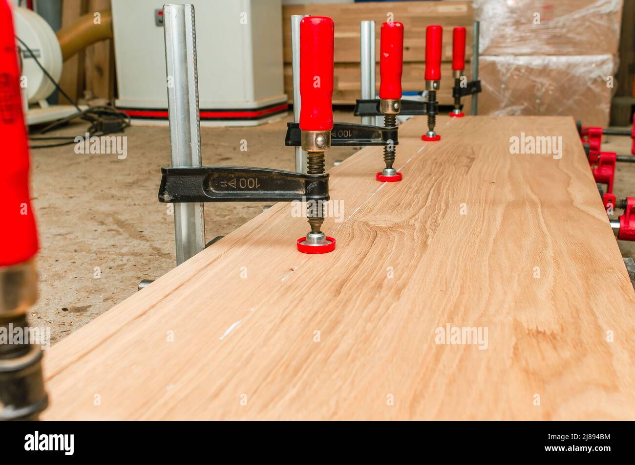 Board with clamps in carpentry workshop. Joinery work Stock Photo - Alamy