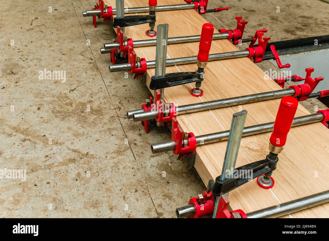 Joiner's clamps on length of bar. Wooden board. Close-up Stock Photo ...