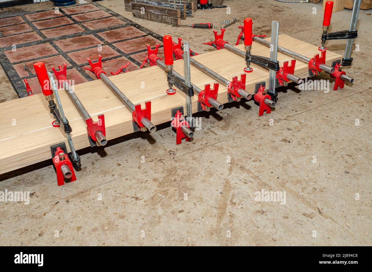 Joiner's clamps on length of bar. Wooden board. Side view Stock Photo ...