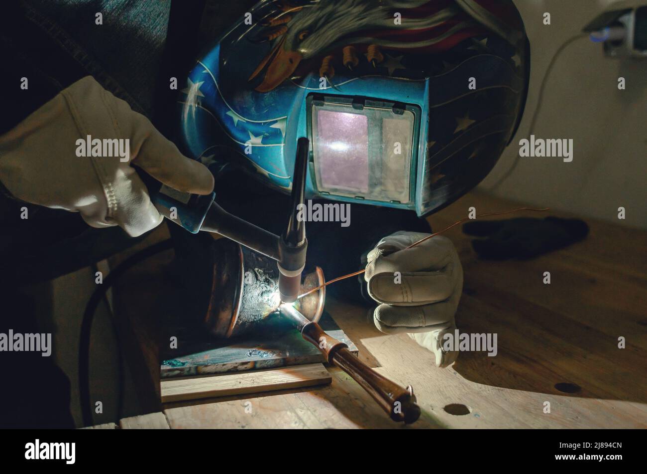 Repair of coffee turk by welding. Master in mask and gloves. Welding works Stock Photo - Alamy