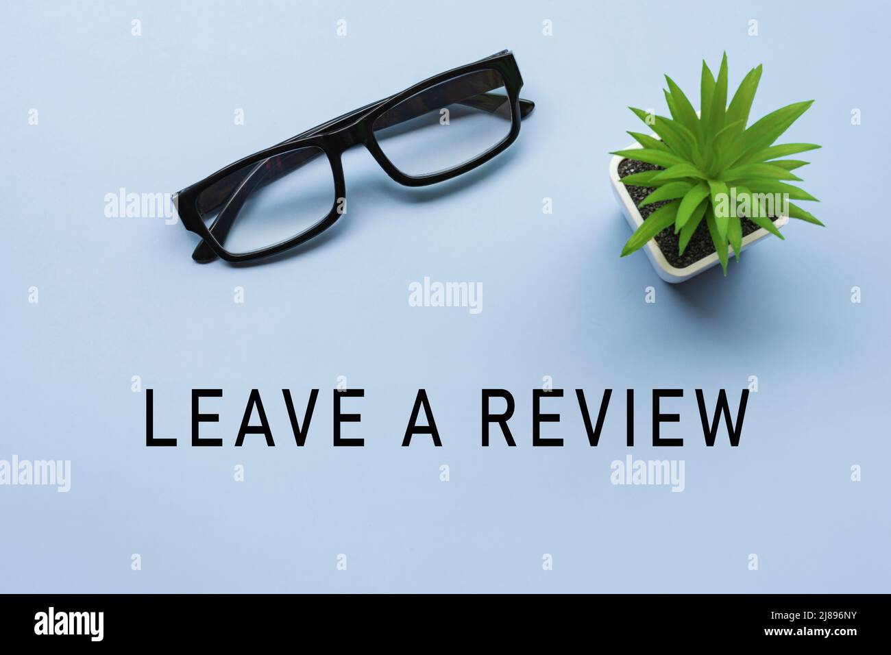 Leave a review text on office desk with potted plant and glasses on ...