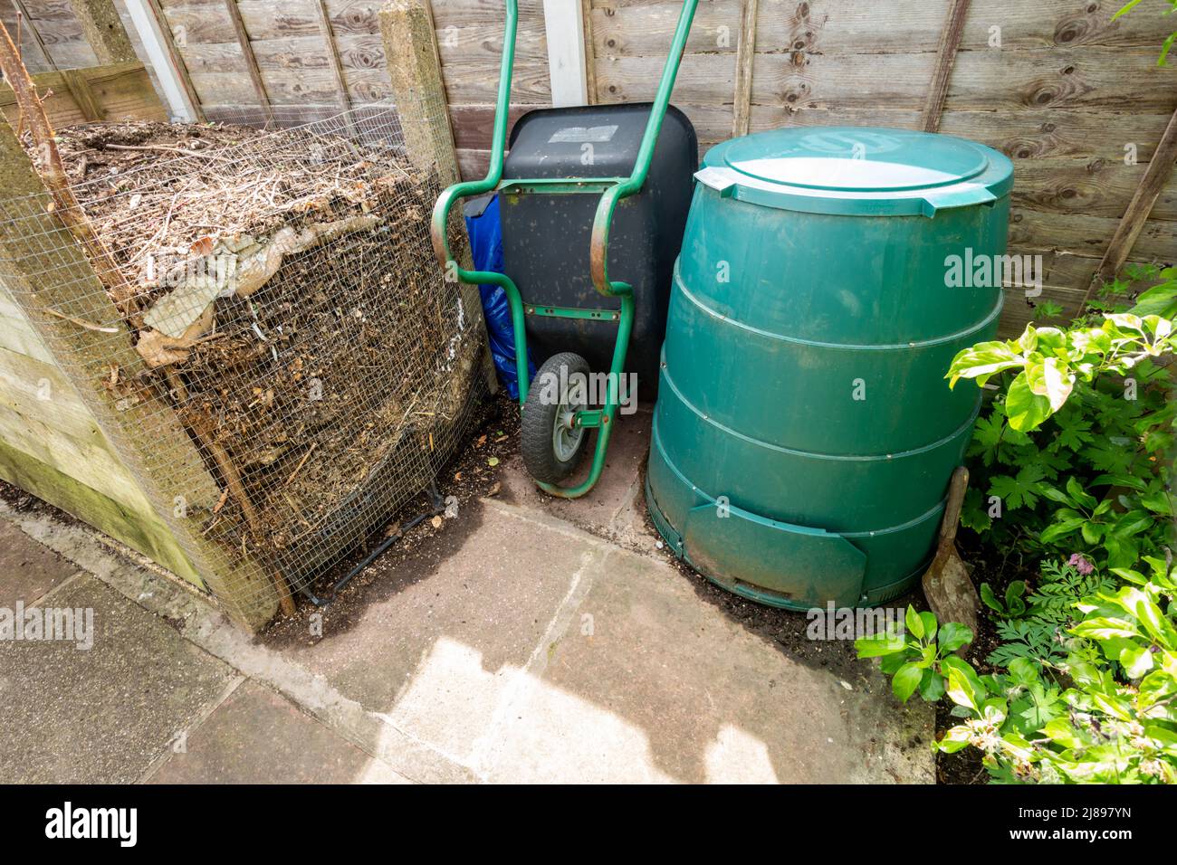 Compost heap, wheelbarrow and water butt in a garden, UK Stock Photo ...