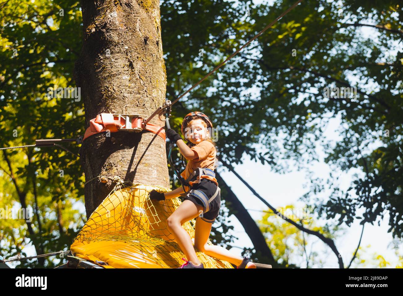 The concentrated girl carefully overcomes obstacles in the rope park ...