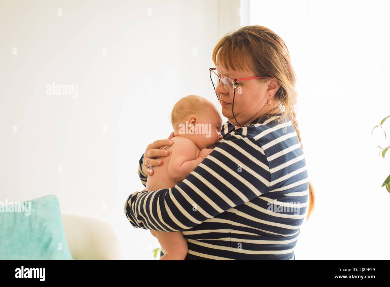 Mother holding her son in her arms. Upset and unemotional woman with newborn baby, feeling ...