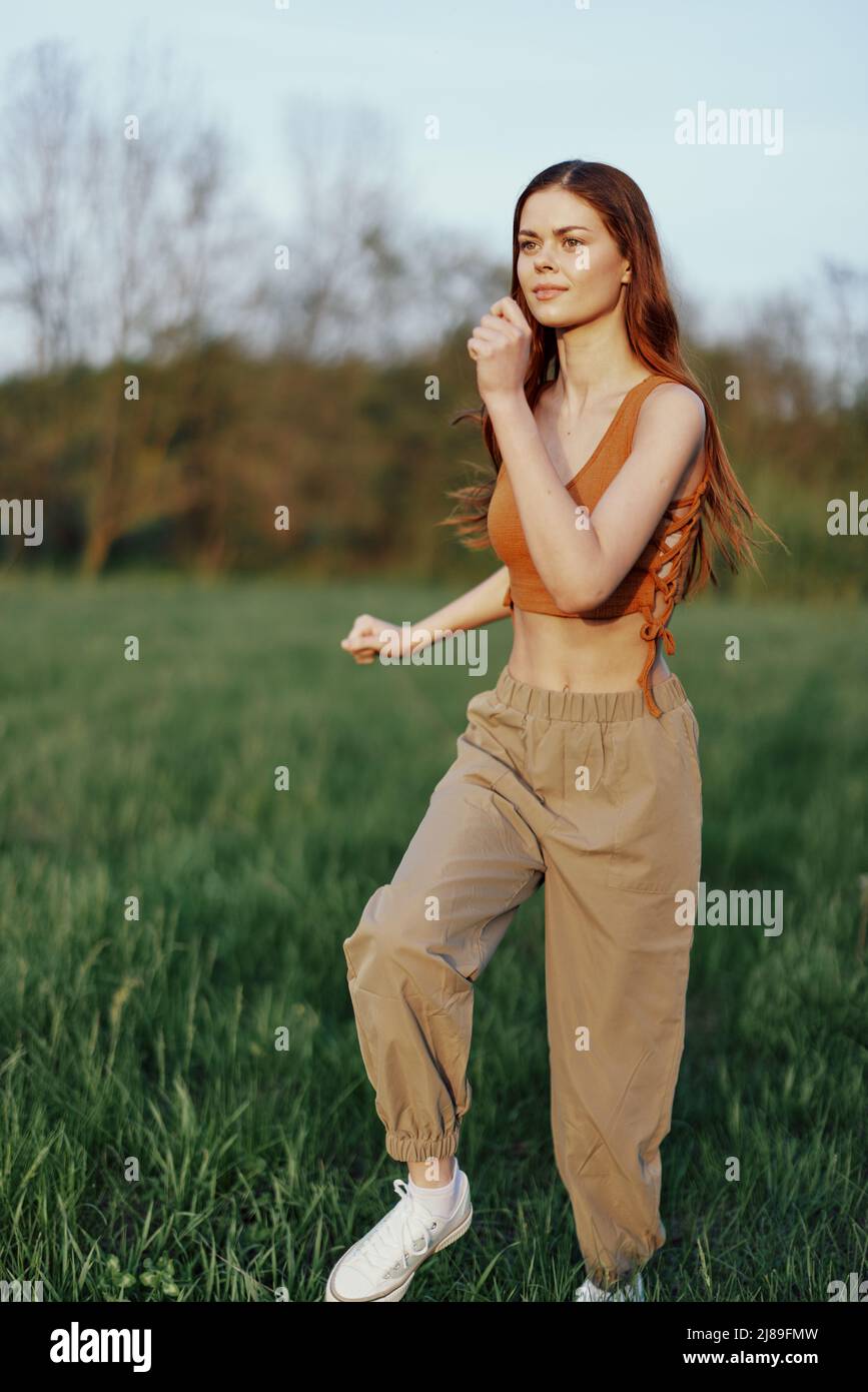 A woman of athletic build runs through the park on the green grass with ...