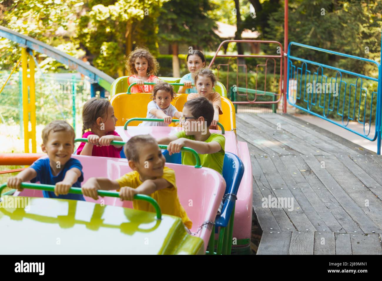 The happy kids on a roller coaster in the amusement park Stock Photo ...