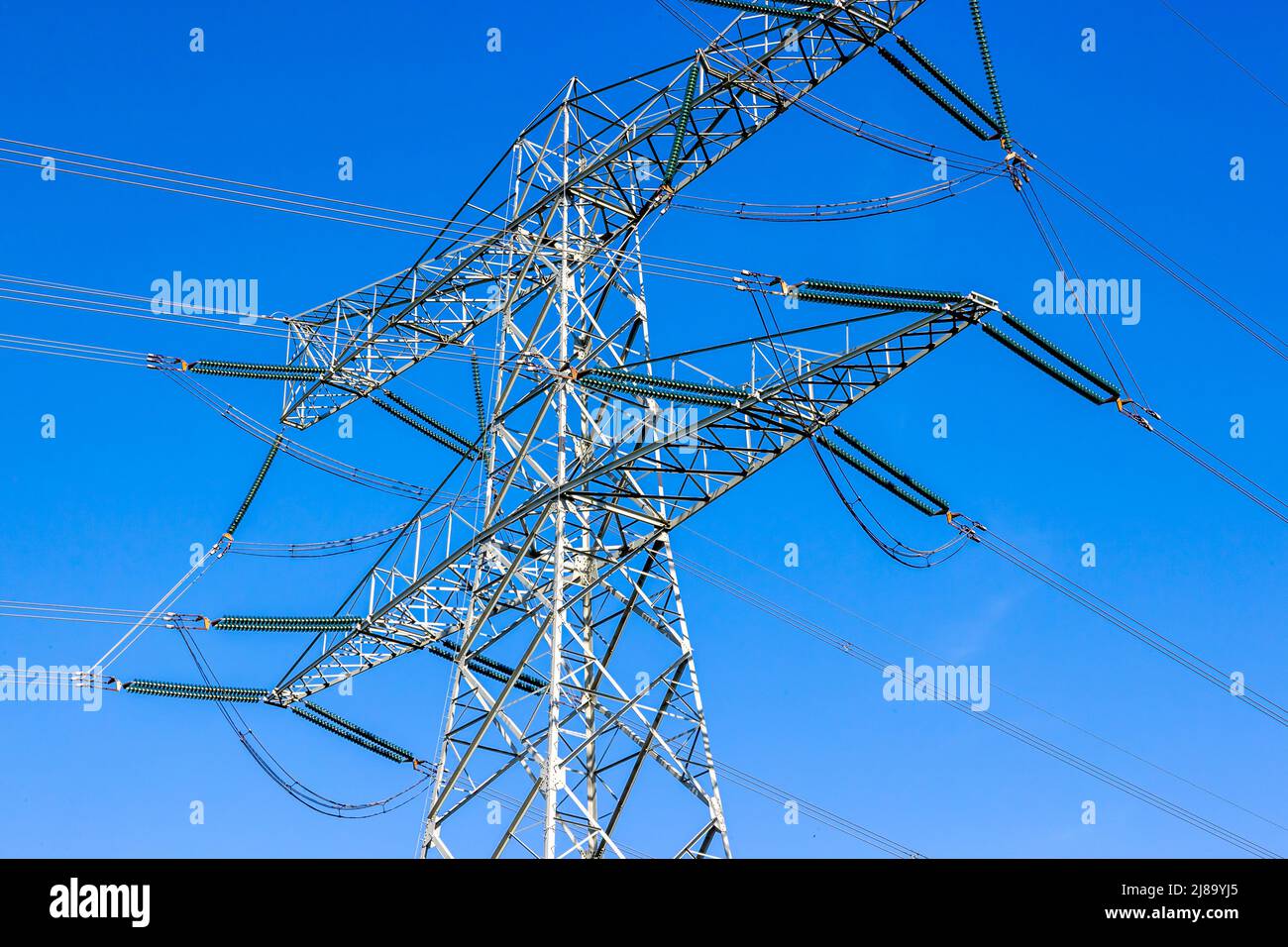 Close-up of the top of a huge high-voltage electric tower, sunny day ...