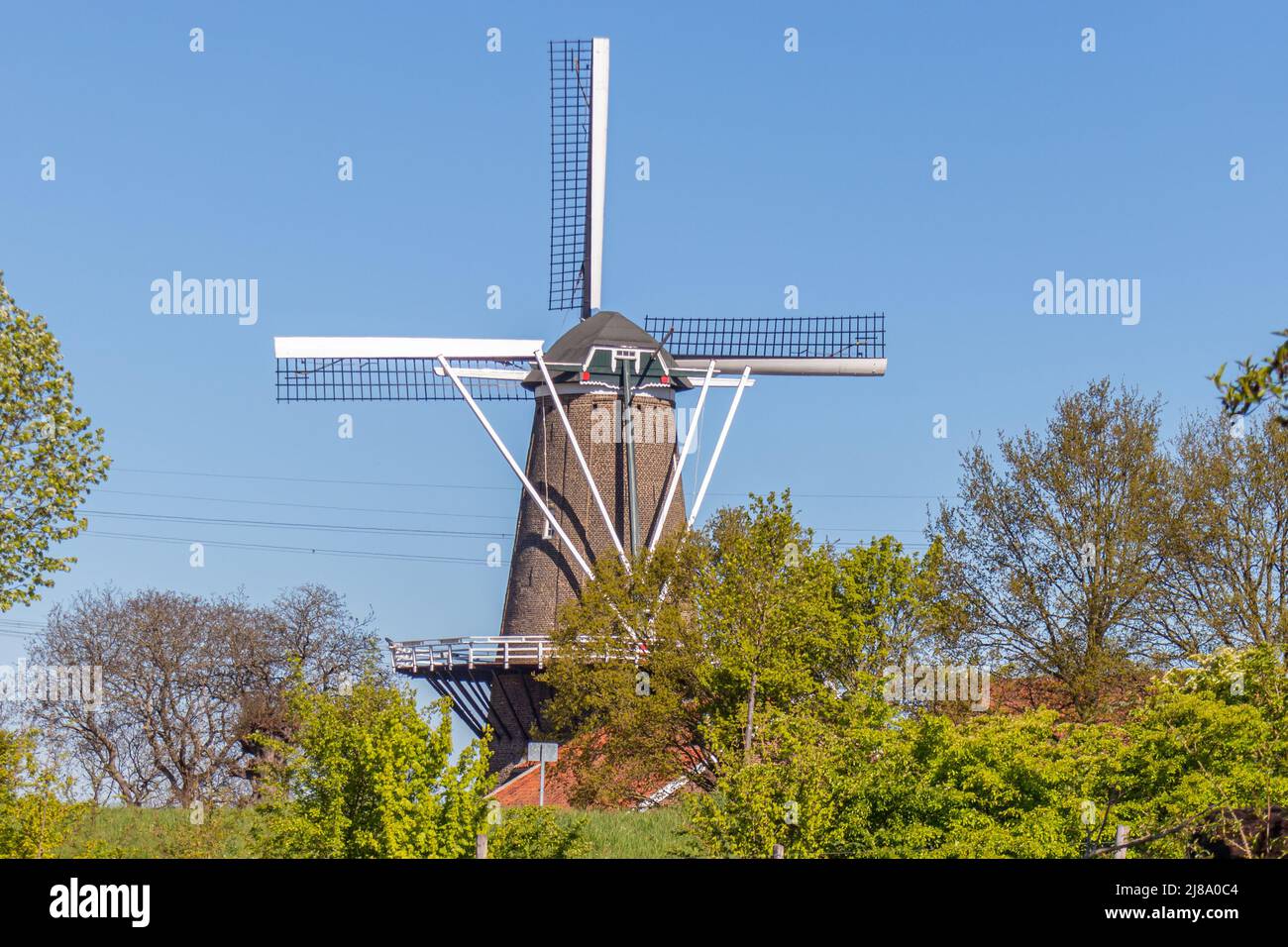 Dutch windmill with its brick tower and blades with white lines ...