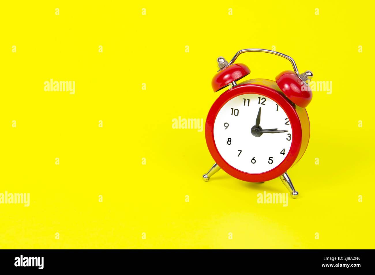 Red alarm clock on yellow paper isolated background with space for text ...