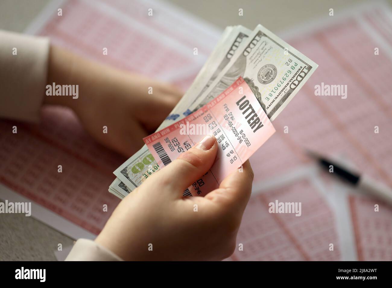 A young woman holds the lottery ticket with complete row of numbers and ...