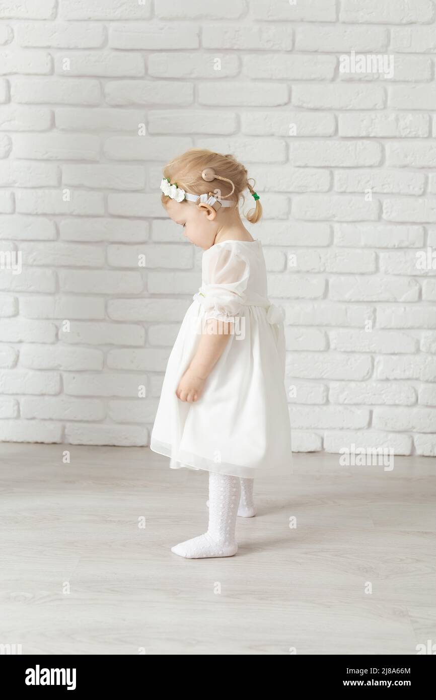 Baby child with hearing aids and cochlear implants on white brick wall ...