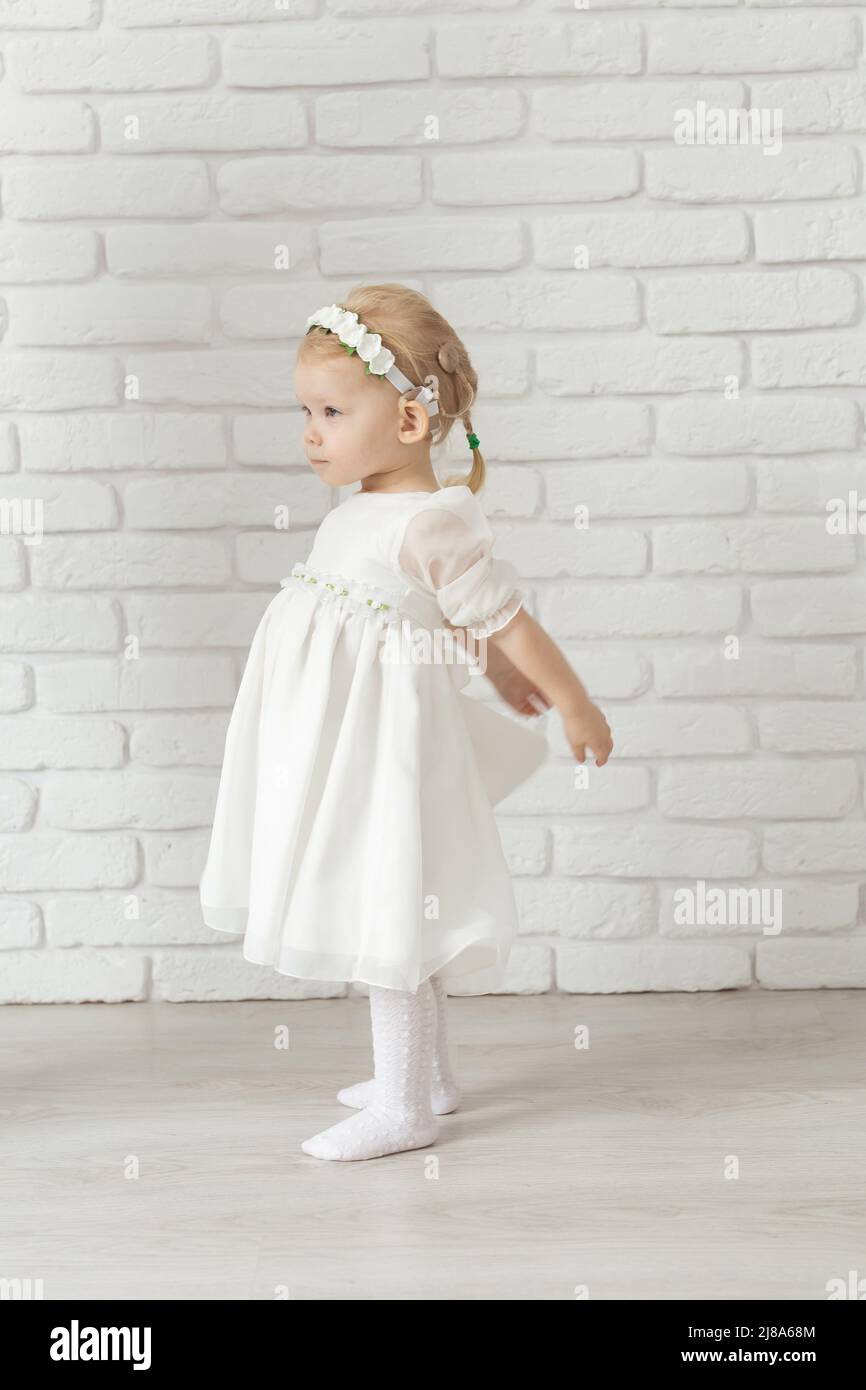 Baby child with hearing aids and cochlear implants on white brick wall ...