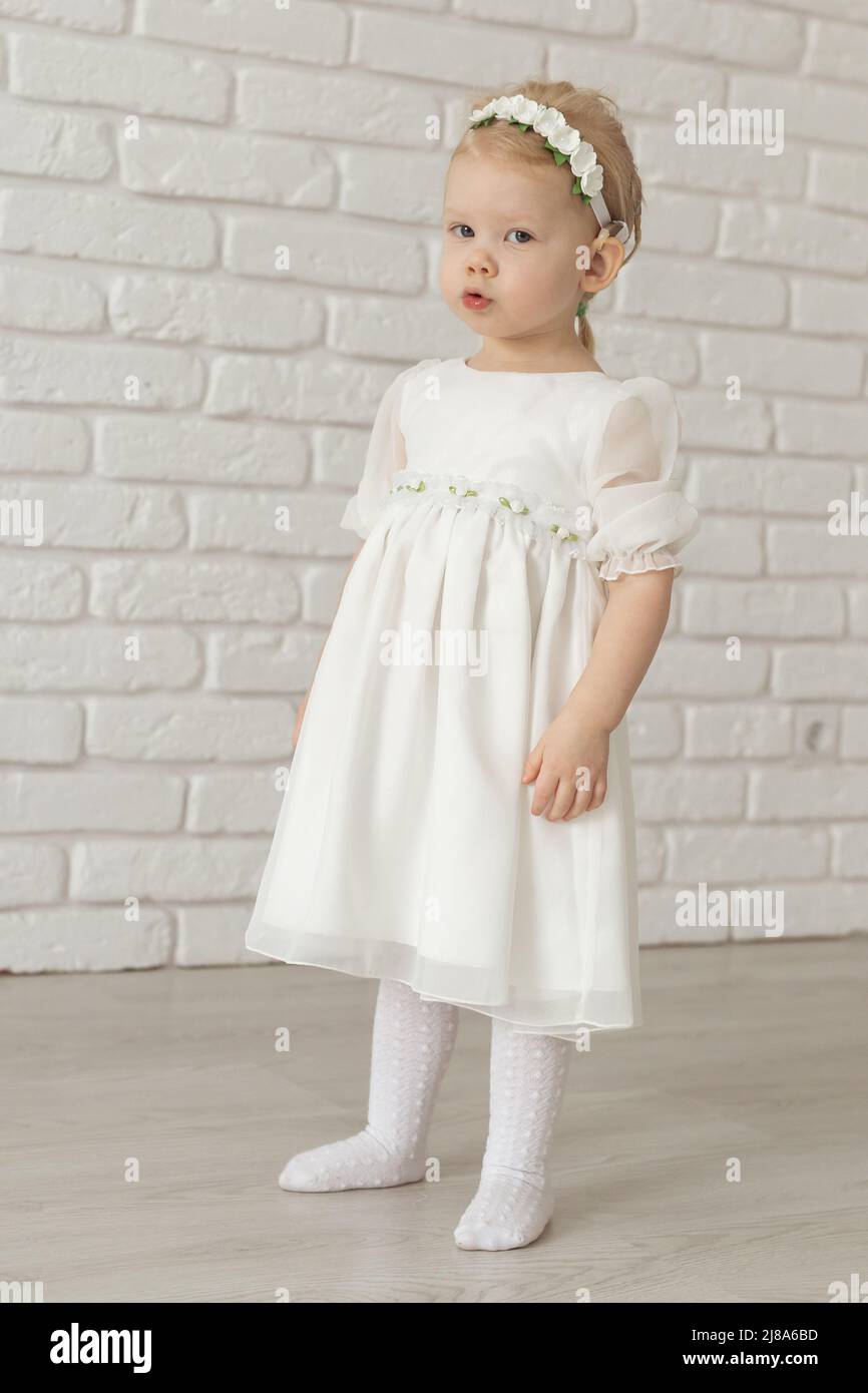 Baby child with hearing aids and cochlear implants on white brick wall ...