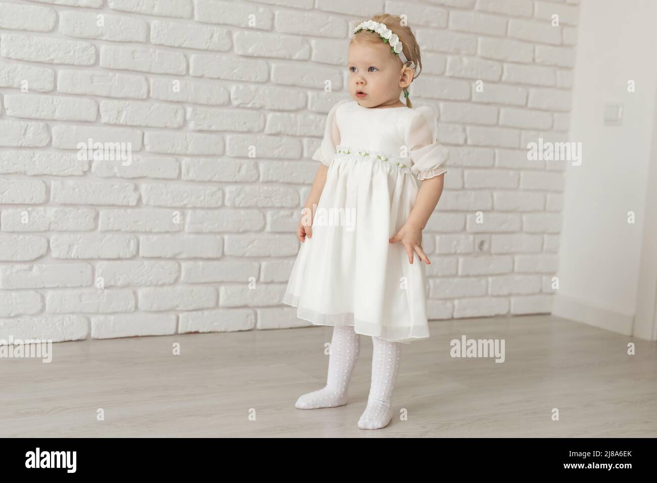 Baby child with hearing aids and cochlear implants on white brick wall ...