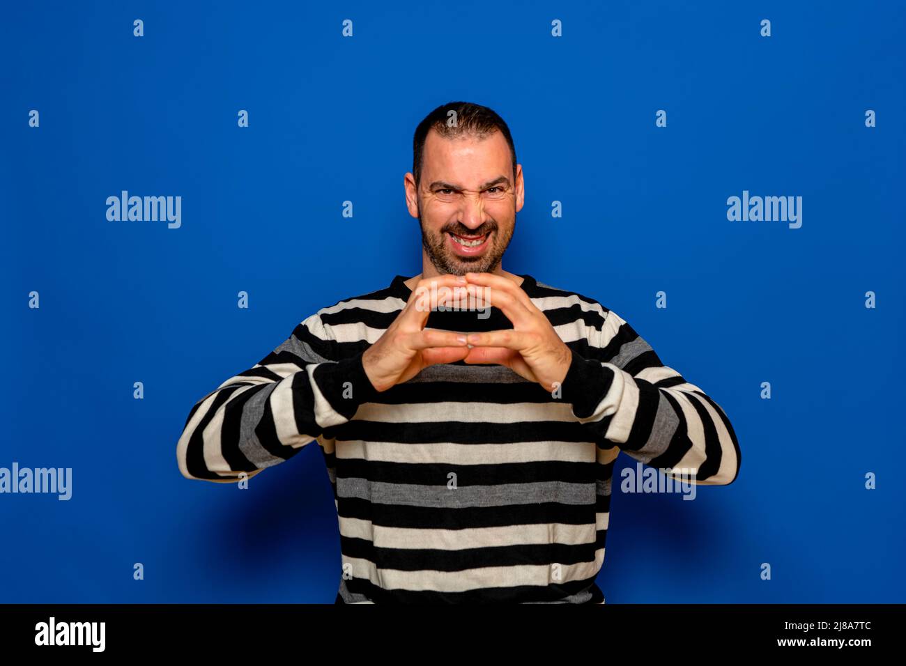 Latino man with beard putting his hands together diabolically showing ...