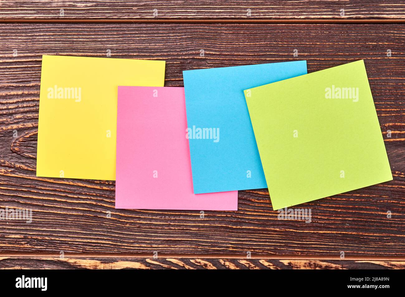 Colorful blank sticky notes with copy space. Brown wooden desk ...