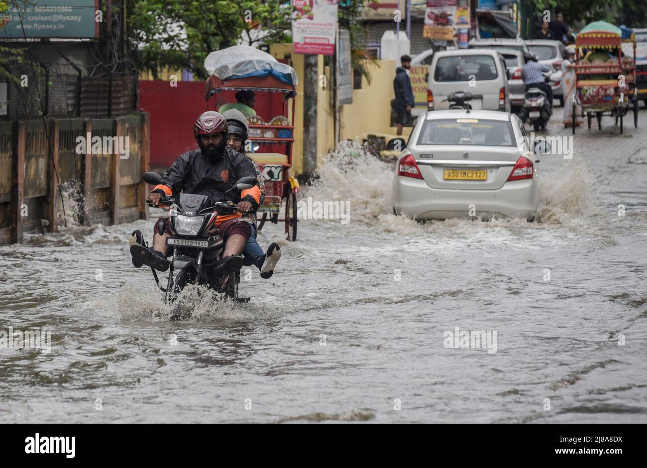 Commuters make their way on a waterlogged street after a heavy rainfall ...
